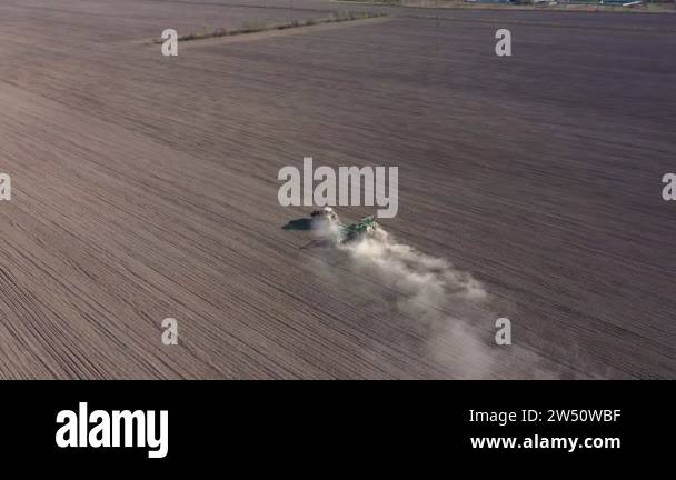 Aerial view of tractor with harrow system plowing ground on cultivated ...