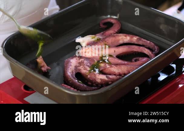 Close up view chef hand pouring sauce at whole boiled octopus ...