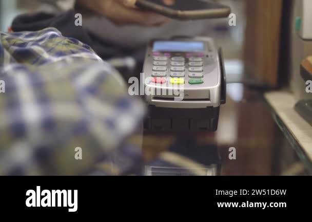 Close-up of cashless payment from smartphone in clothing shop ...