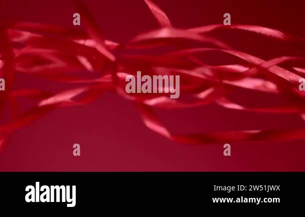 Red silk shiny ribbons falling down on a matte background. 4k quality ...