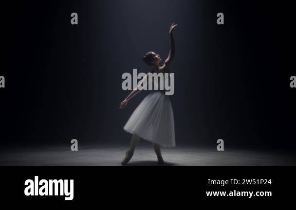 Flexible ballerina standing under spotlight. Ballet dancer moving hands ...
