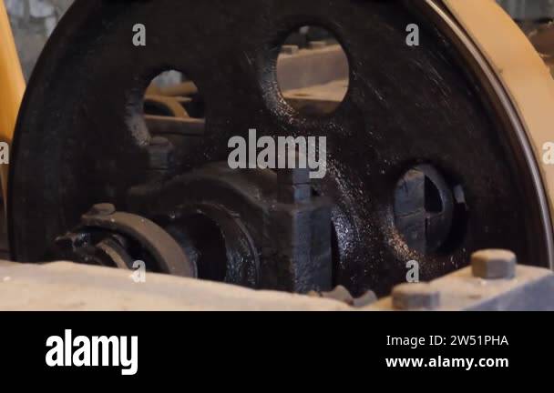 Close up of large heavy old flat belt pulley spinning as part of ...