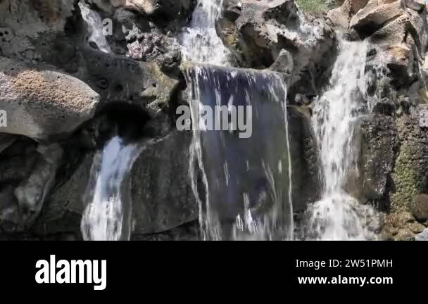 A beautiful small artificial waterfall among huge stones and ornamental ...