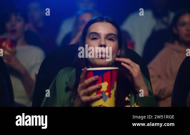 Shocked woman jumping at scary moment in cinema. Scared girl watching ...
