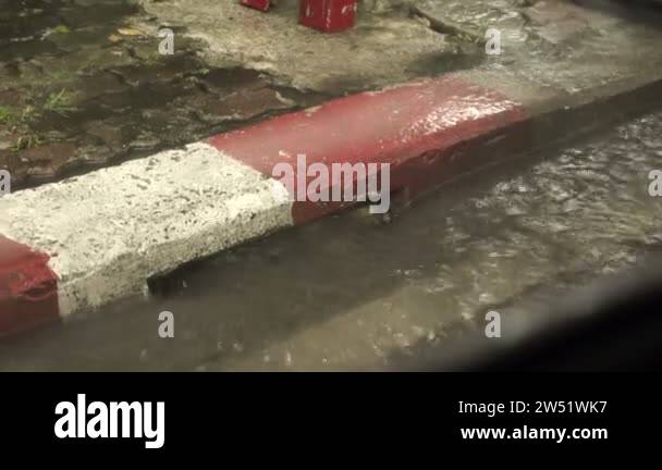 Water draining down roadside gutter flooding during rain strom season ...