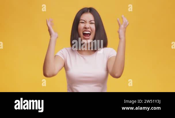 Young furious asian woman screaming loud and shaking hands, feeling ...
