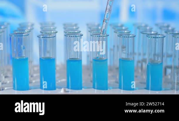 Lab assistant adding green liquid in test tube, monitoring chemical ...
