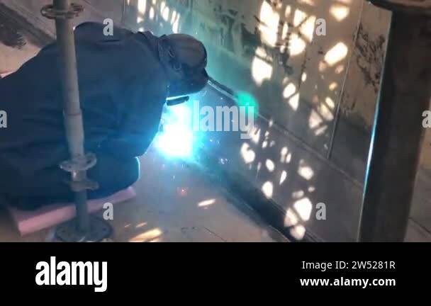 Construction worker is welding parts of industrial building with lots ...