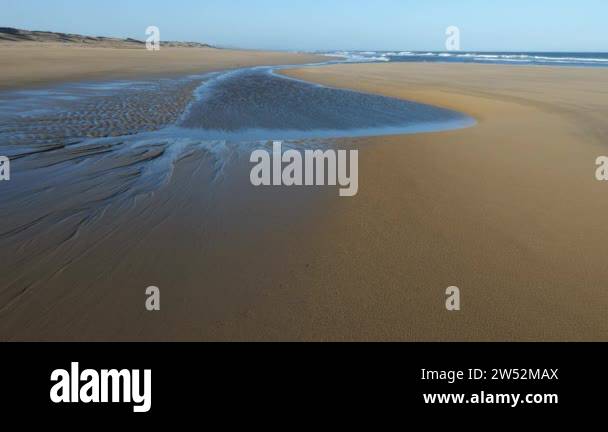Calm scene of a water puddle on beach sand with clean clear seawater ...