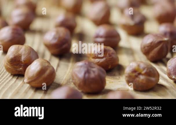 Sliding shot of dried hazelnuts lying on a textured wooden table ...