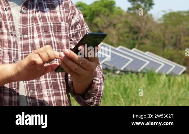farming man holding a black smartphone Used to control solar panels ...