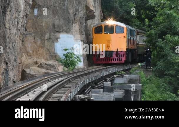Train running on track between hellfire pass mountain and riverside Sai ...