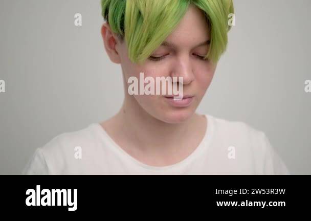 A young girl with a short pixie haircut and green hair in a white T ...