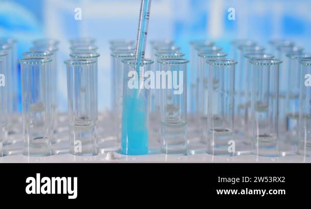 Scientist injecting chemicals into test tubes. Test tube of colored ...