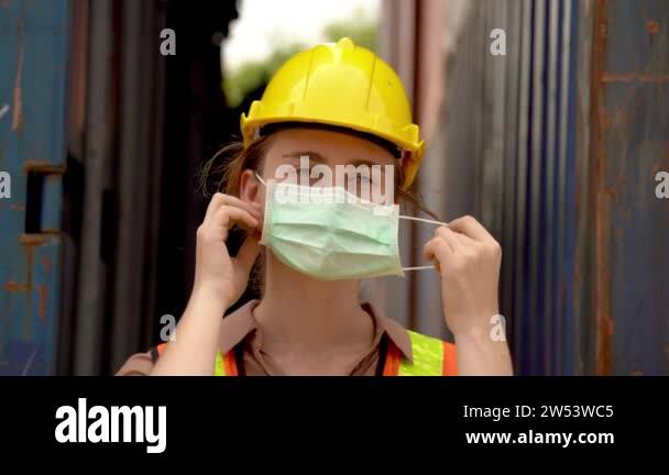 Labor woman worker takes off protection mask face and safety helmet and ...
