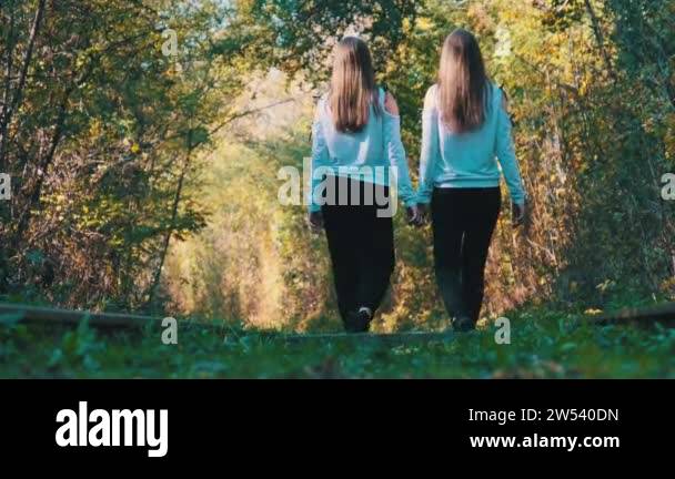 Twins Girls Holding Hands Walking Along Railroad Tracks. Back view ...
