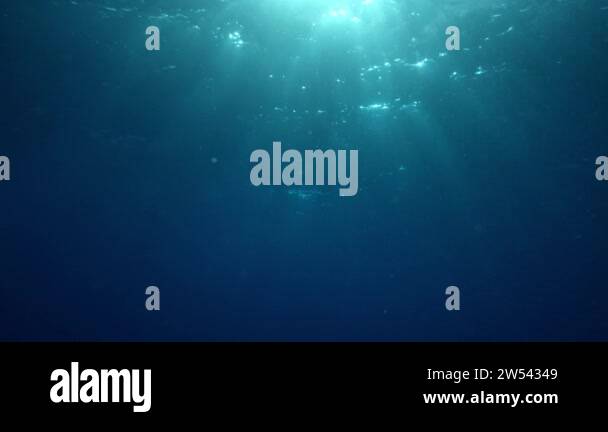 Sunbeams penetrating wavy ocean surfaces. Ocean background light shafts ...
