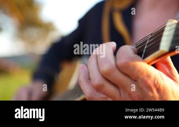 Man plays a guitar and sings outdoor songs at sunset. Hand on the ...