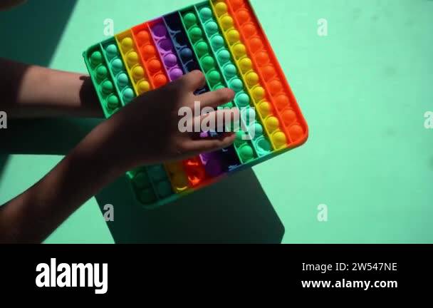 Bright silicone striped toy Big Pop It. Kid playing with rainbow pop it ...