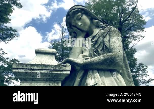 Figure of a praying angel. A very ancient stone statue. . Sad angel as ...