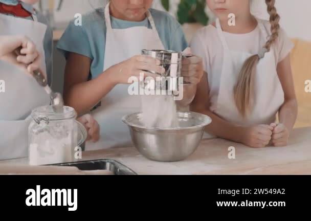 Close-up of unrecognizable child scooping flour with spoon out of jar ...