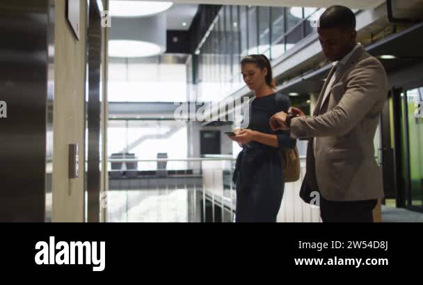 Diverse businessman and businesswoman waiting for lift and arriving in ...