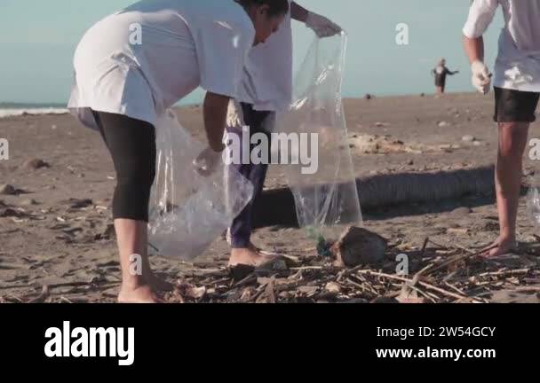 Young indonesian group of environmentalists bending over cleaning ...