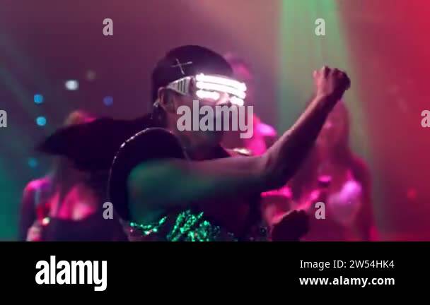 Group of people dance in disco night club to the beat of music from DJ ...