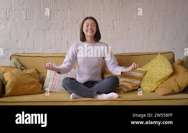Mindful calm beautiful mixed race woman sit at sofa doing yoga breath ...