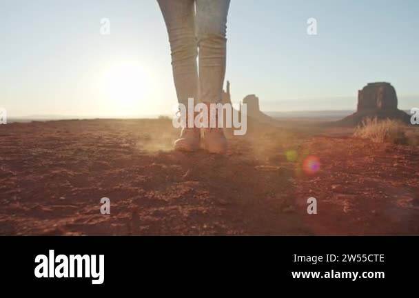 Low view of female feet in boots steps at red desert landscape, woman ...