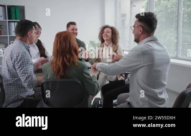 successful work team, young joyful employees hold hands then clap each other during corporate ...