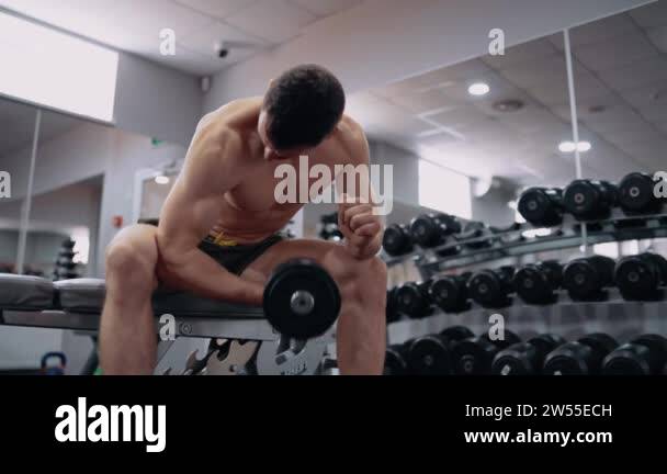The young coach shows how to correctly lift the dumbbell with one hand ...
