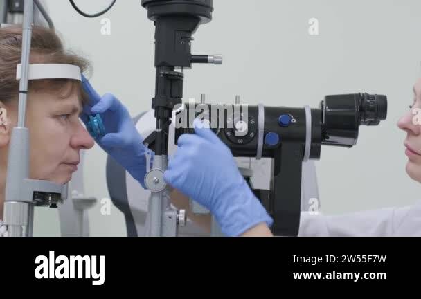 Woman doctor is viewing through ophthalmoscope in eyes of patient in ...