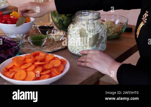 Filling a jar with cabbage, adding bay leaves for flavor. Fermenting ...