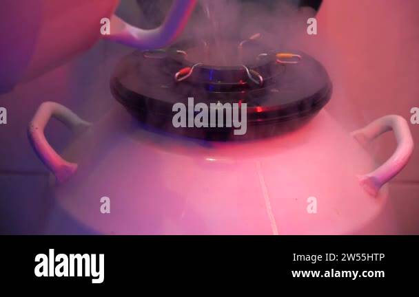 Scientist opens a Cryogenic container with medical samples and pour ...