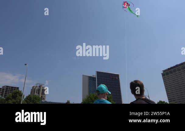 Father teach young boy to fly kite high in sky between skyscraper. 4K ...