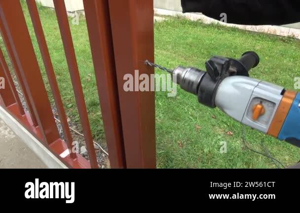 Building a metal fence with a drill and screw. Man hands drilling metal ...
