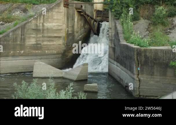 Water discharge through an old dam on the river. An abandoned hydraulic ...