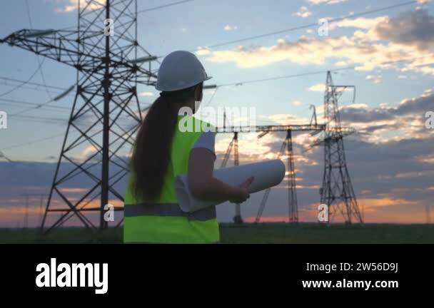 An electrician on the background of high towers of power plants looks ...