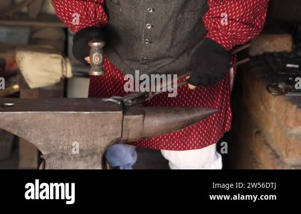 Hot piece of iron being beaten on an anvil by a blacksmith with a ...