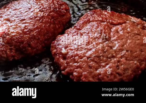 Man is frying meat on old pan for the burger cutlet at the kitchen. Oil ...