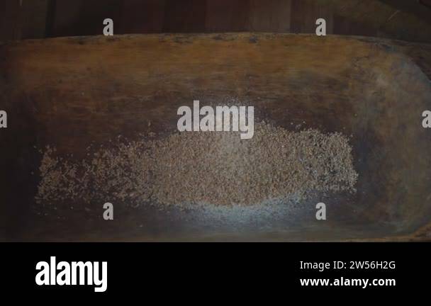 The ancient Quern stone hand mill with grain. The man grinds the grain ...