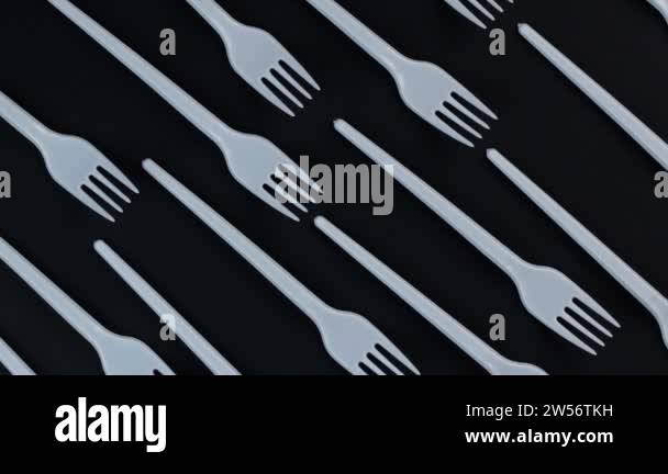 Eco concept. Plastic disposable forks stacked in rows on a black ...