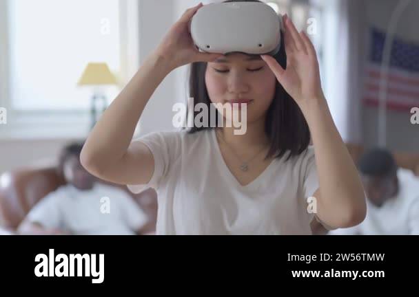 Positive Asian woman taking off VR headset showing thumb up looking at ...
