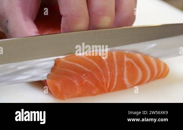 A sushiman slicing a salmon steak with his Japanese knife. Preparing ...