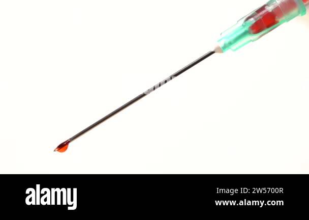 Drops of blood from the tip of the medical syringe. Bloody liquid ...