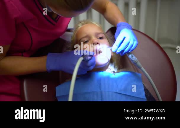 Lady stomatologist polishing little girls tooth enamel, oral cavity ...