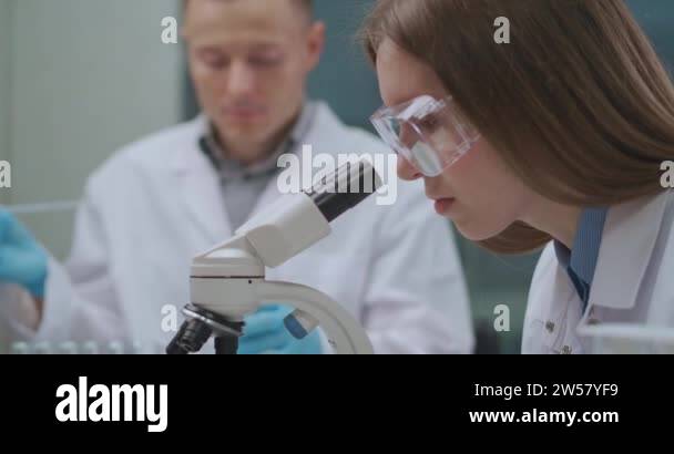 team of forensic experts is working in crime laboratory, researching evidence, woman is viewing ...