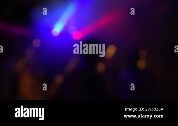 Neon lights on the dance floor. Blurry bokeh. People are jumping on the ...