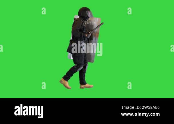 Policeman in full uniform running with a shield and baton on a Green ...